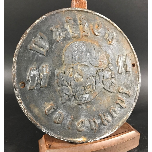 A WAFFEN SS CAST DEATH HEAD ROUNDEL. A circular cast iron pl... | Barnebys