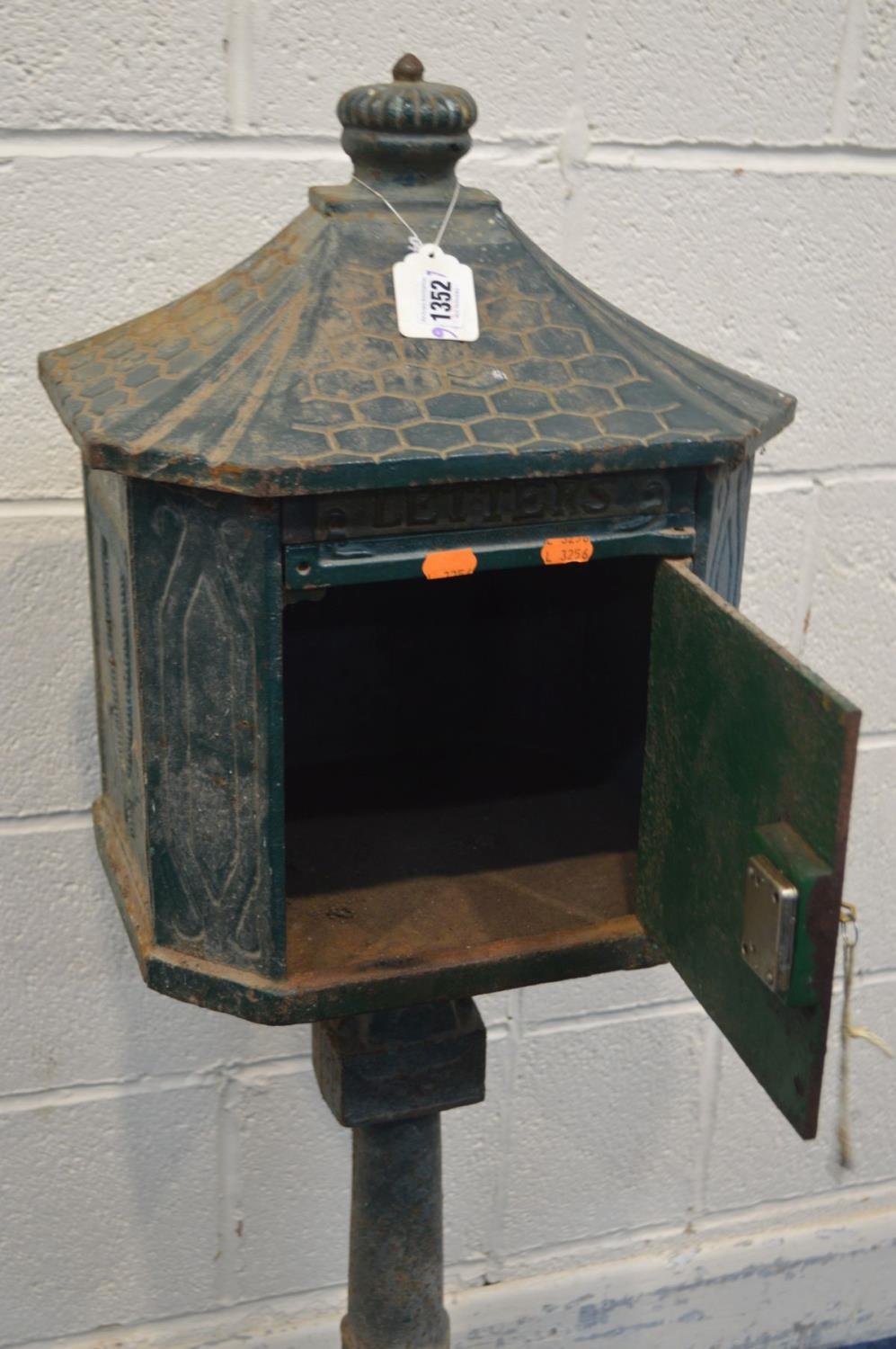 A GREEN PAINTED CAST IRON LETTER BOX on a stand (one bolt missing ...