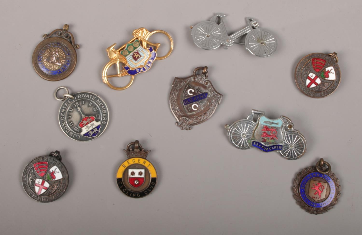 A collection of cycling badges and medals including enameled examples.