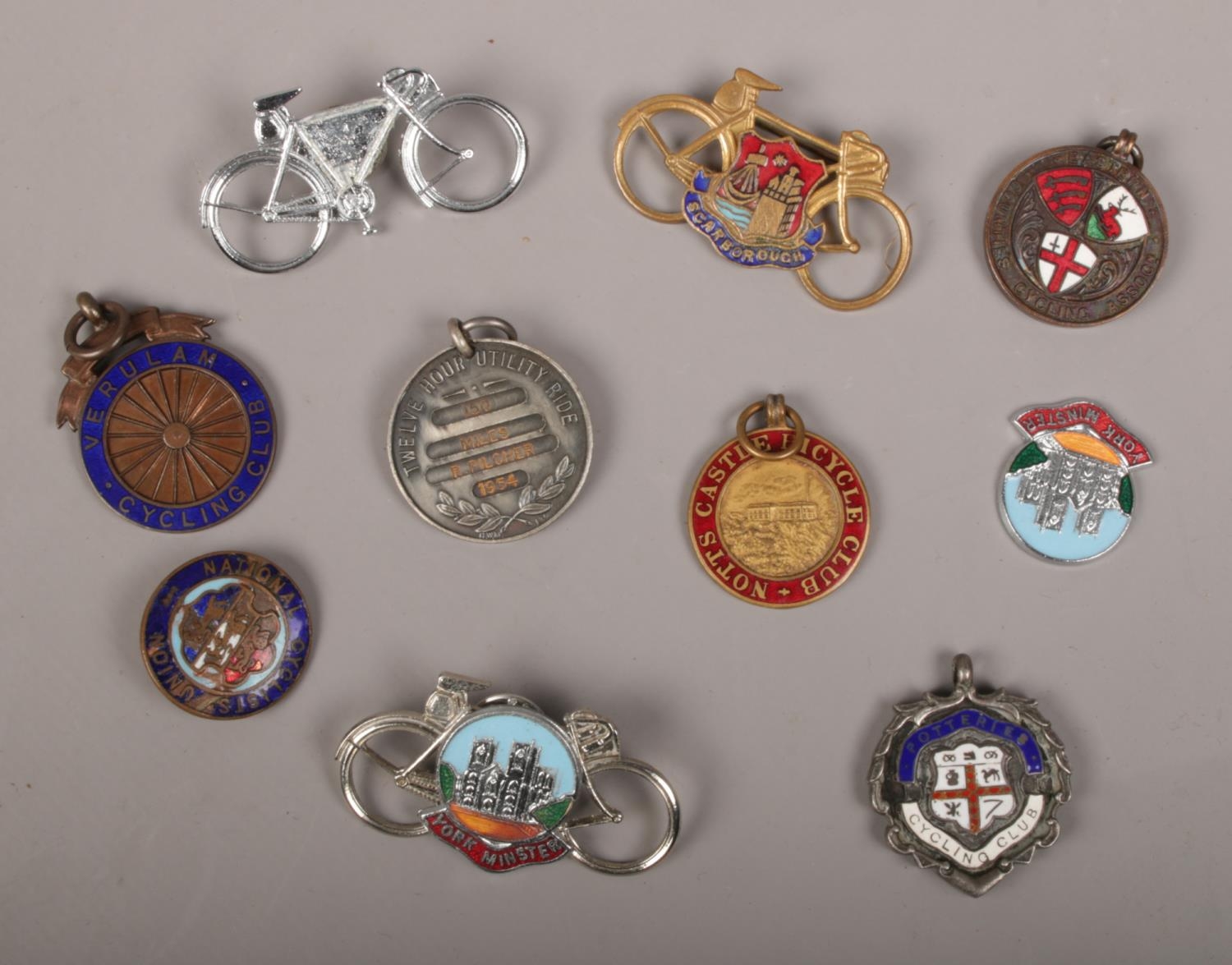 Nine vintage cycling badges and medals including enameled examples.