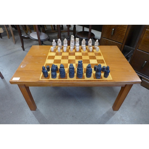 A teak chess table, with resin chess set | Barnebys