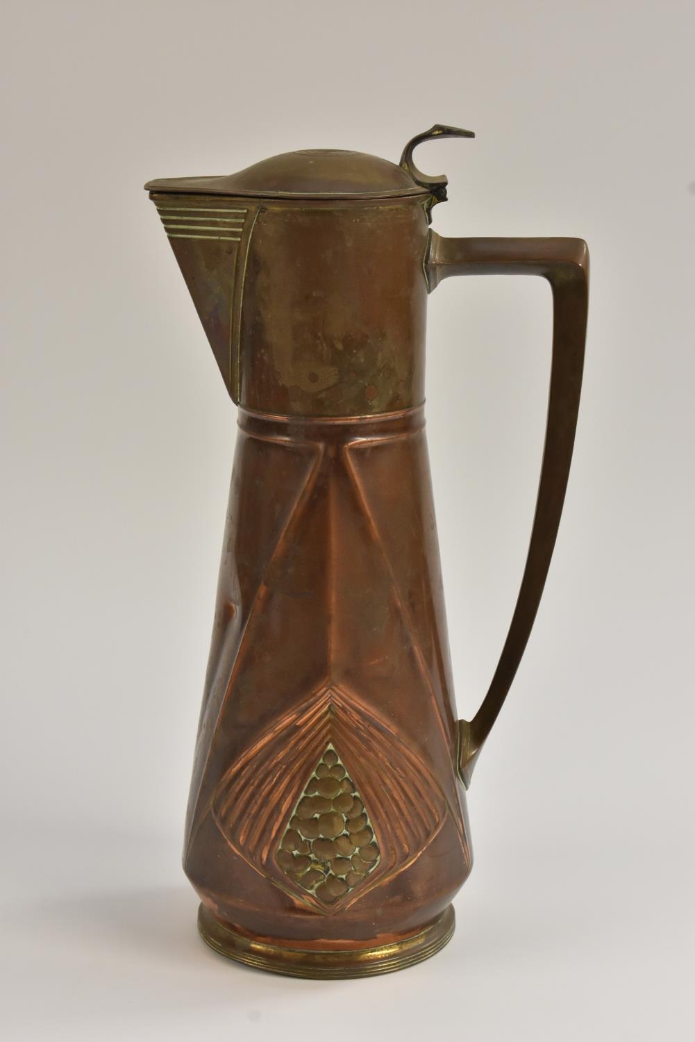 An Orivit Arts and Crafts copper tapering cylindrical jug, the domed ...