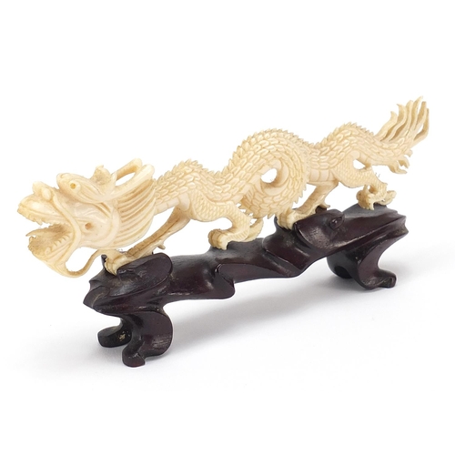 Chinese ivory carving of a dragon raised on hardwood stand, ... | Barnebys
